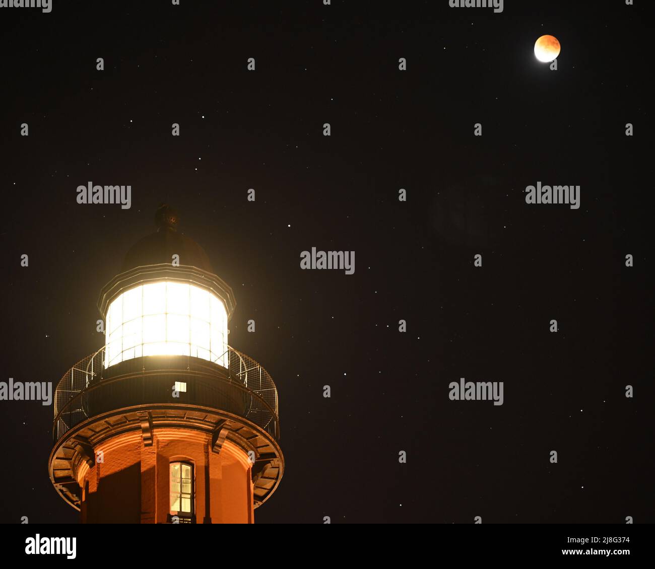 An eclipsed moon hangs over the historic Lighthouse in Ponce Inlet ...