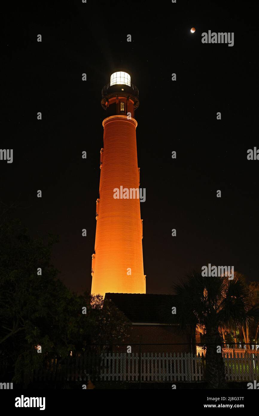 An eclipsed moon hangs over the historic Lighthouse in Ponce Inlet ...