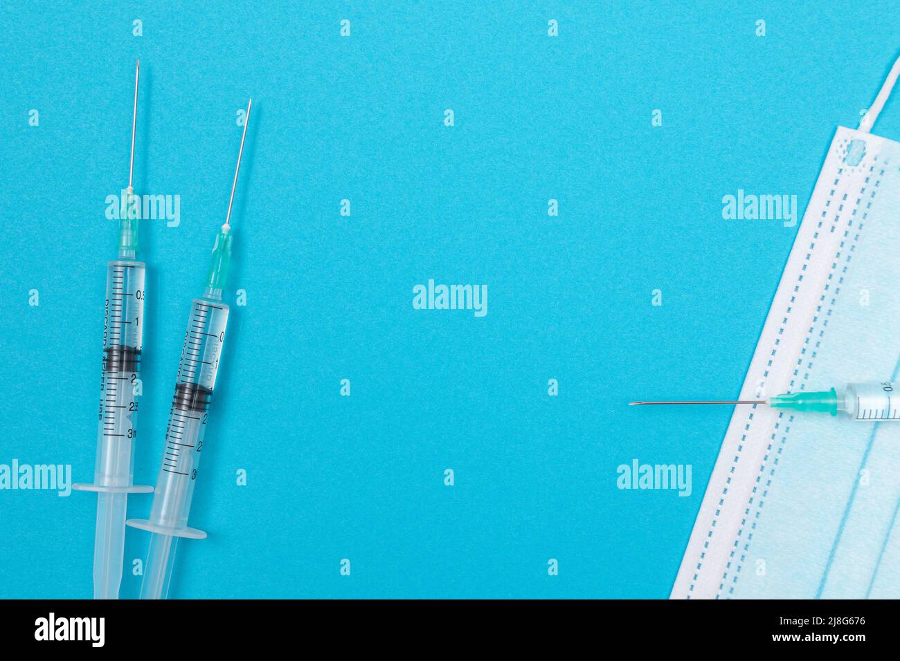 Several Syringe and Face Mask on Blue Table - Top View. Syringes are ...