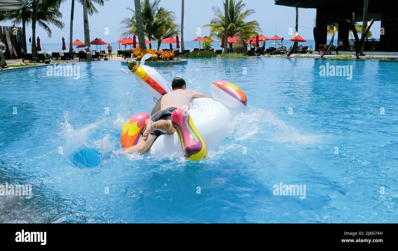 Happy funny man successfully jump onto floating inflatable unicorn in ...