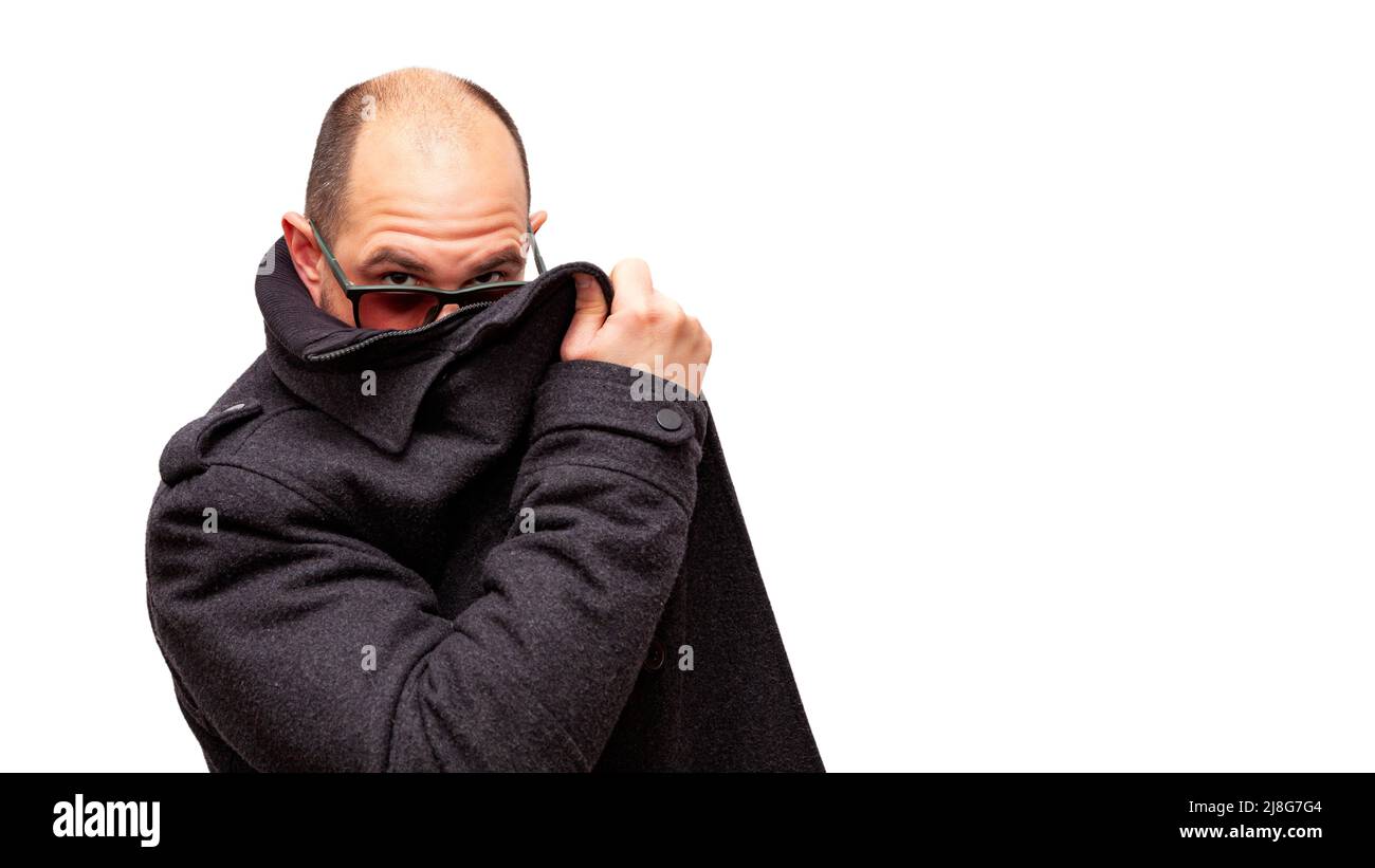 A bald adult male wearing sunglasses hides behind his dark jacket and ...