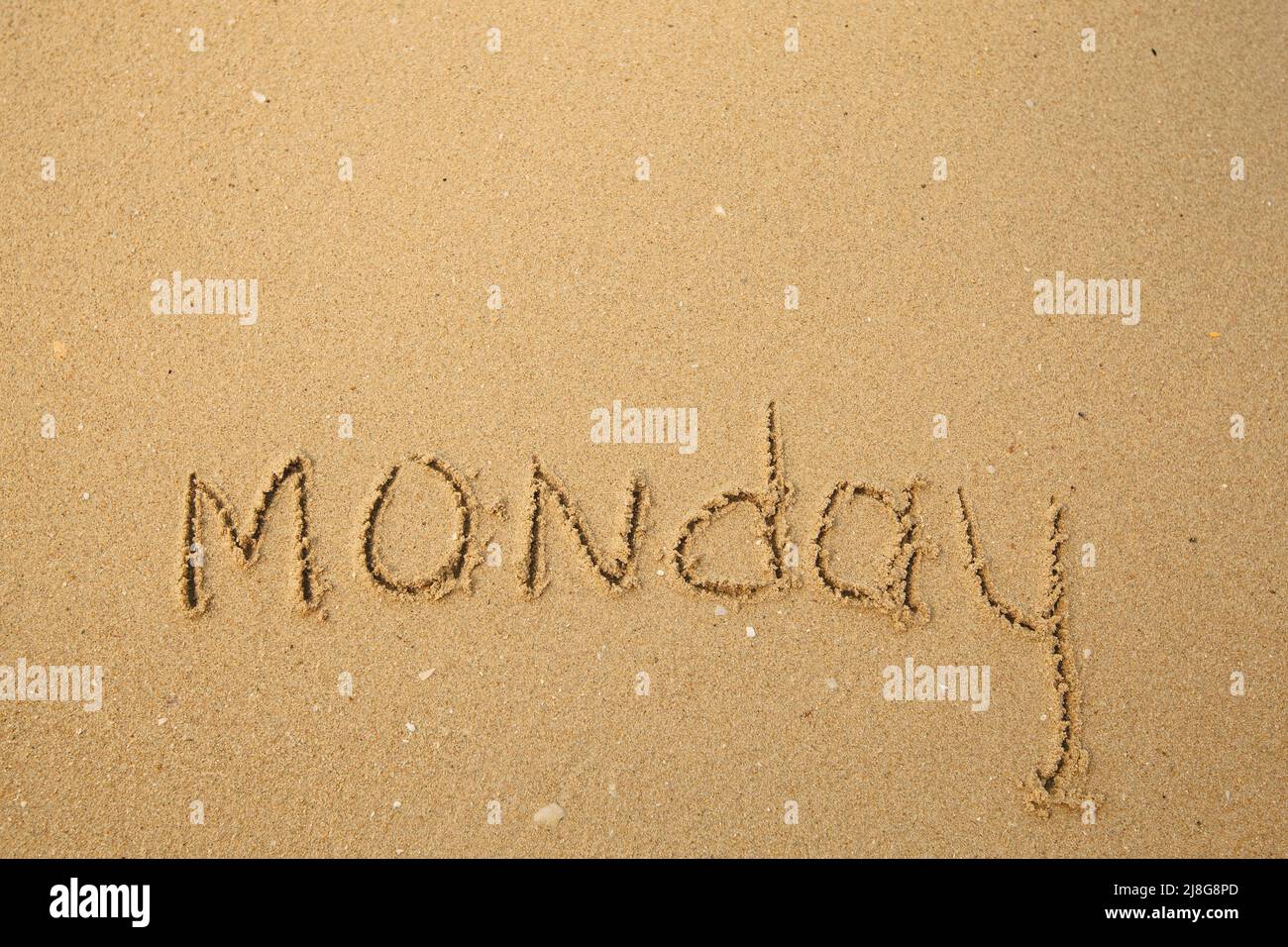 Monday - drawing of days of the week, handwritten on the sea beach sand ...