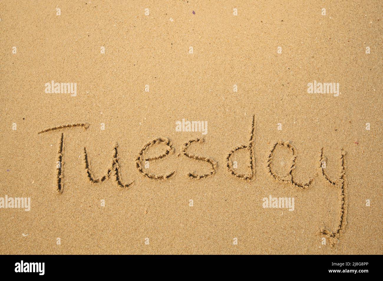 Tuesday - drawing of days of the week, handwritten on the sea beach ...