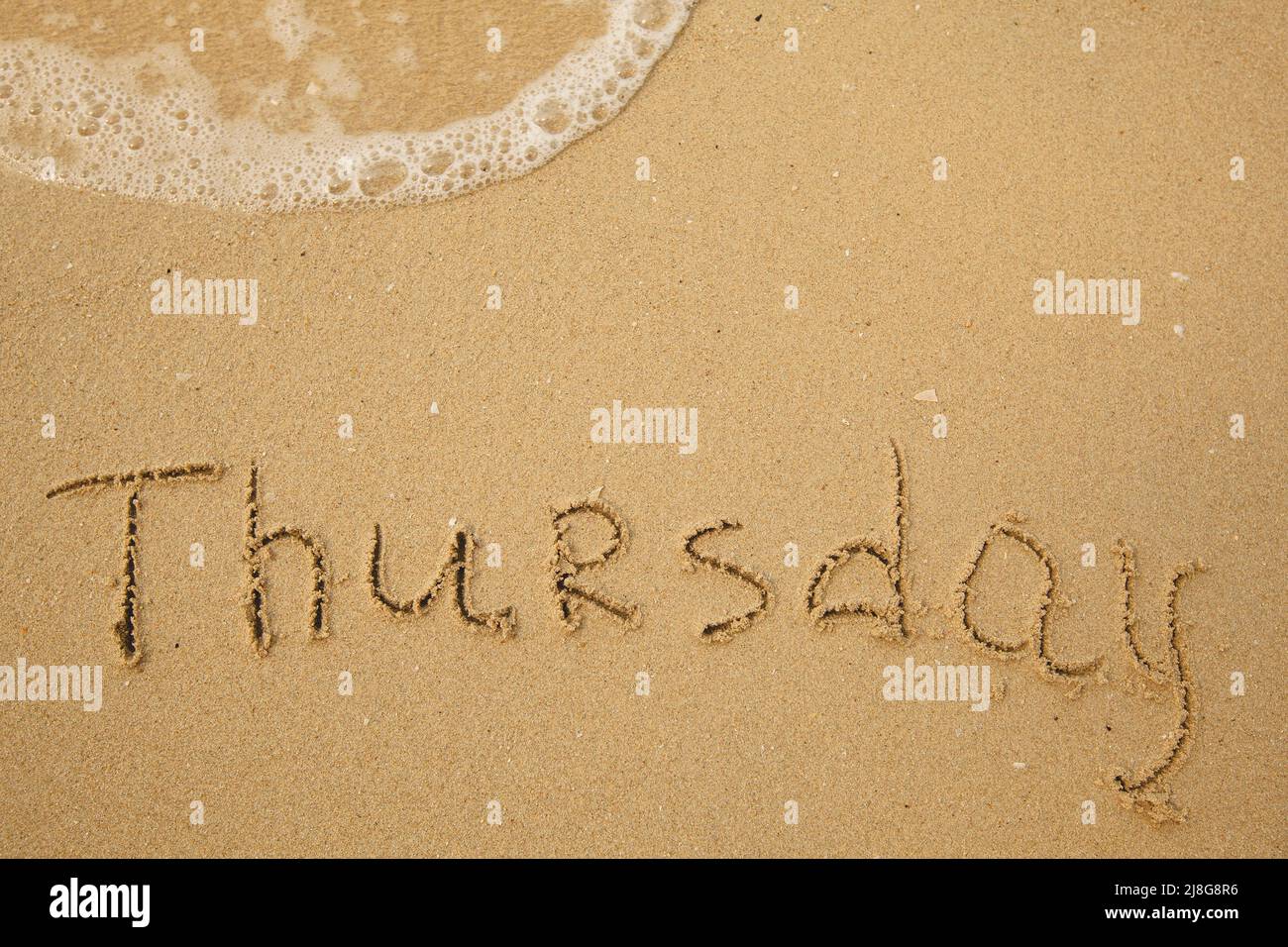 Thursday - drawing of days of the week, handwritten on the sea beach ...