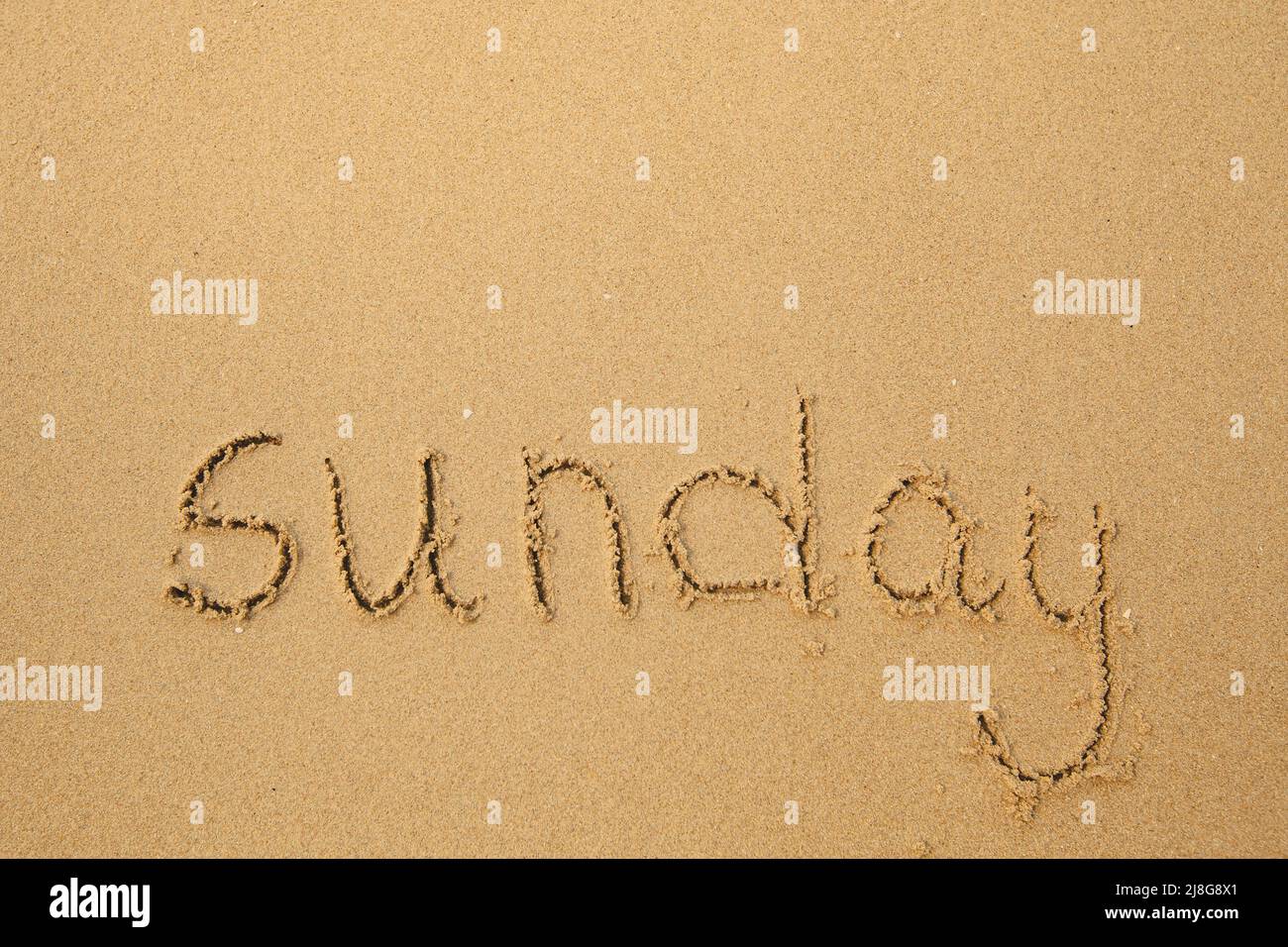 Sunday - drawing of days of the week, handwritten on the sea beach sand ...