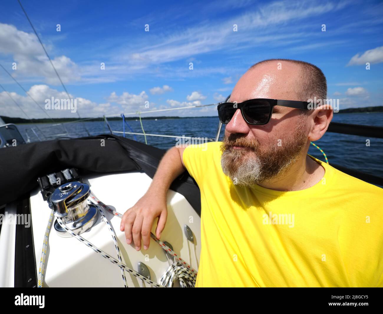 one smiling bearded adult man sailing on a sailboat during his yacht ...