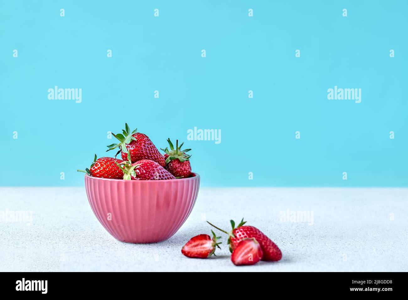 Fresh red ripe organic bio strawberries in red bowl on light blue ...