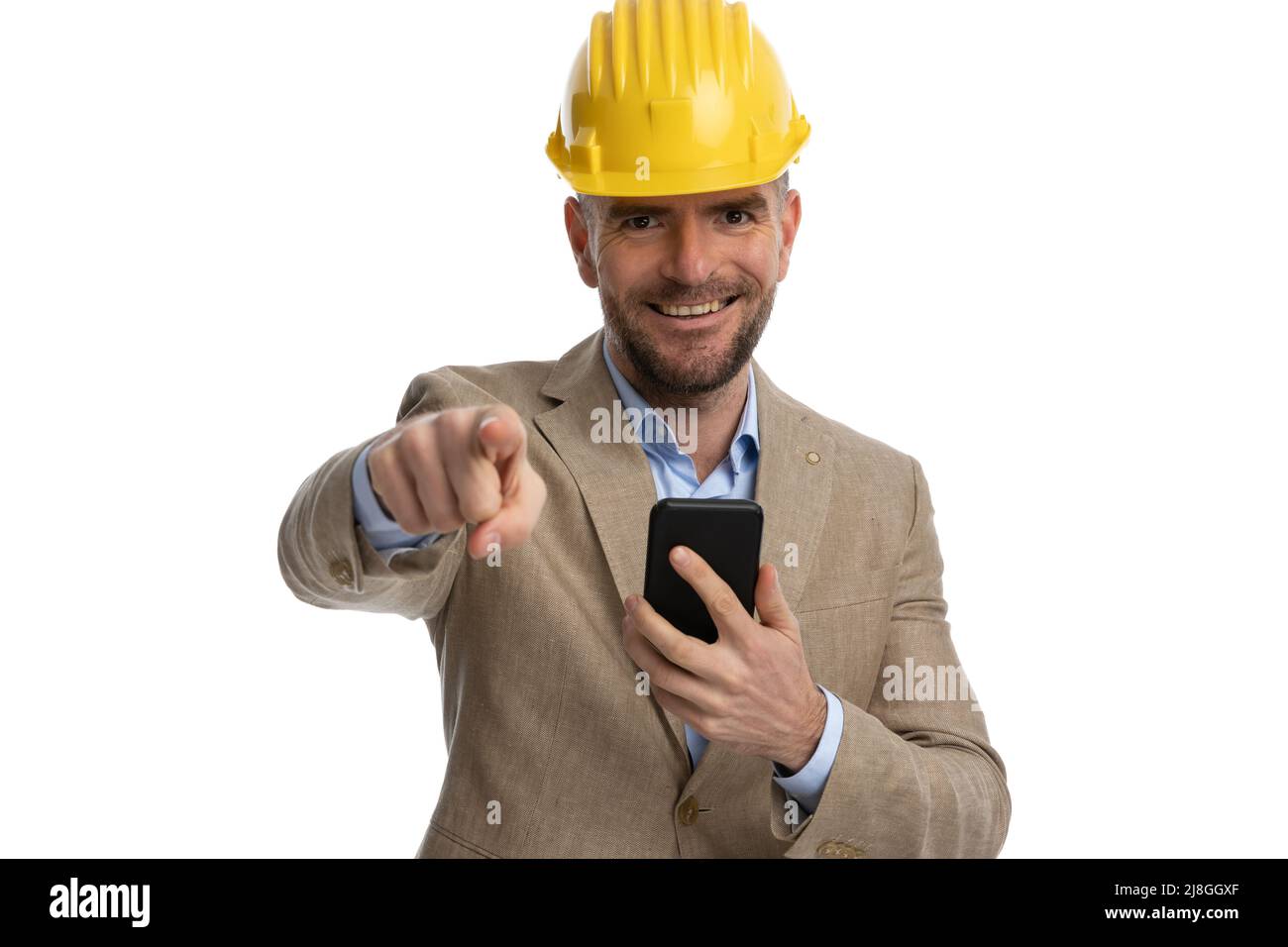 portrait of happy engineer man with helmet holding mobile and pointing ...