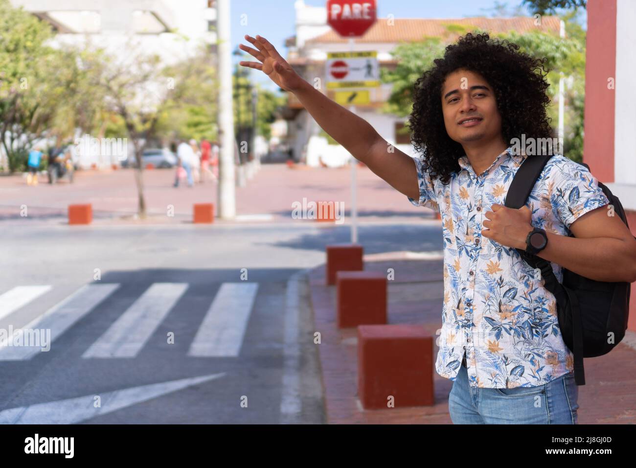 Afro man raising his hand hailing a cab on the street. Young Hispanic ...