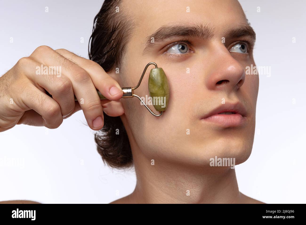 Skin care. Young attractive man with perfect smooth skin, applying face ...