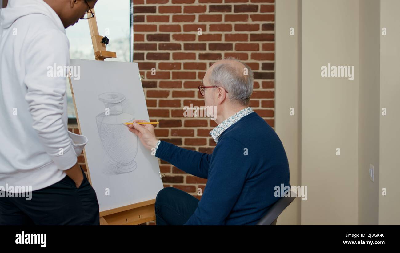 Elder person attending art class lesson with young teacher to develop ...