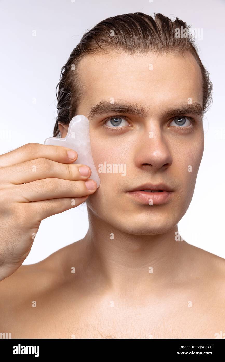 Massage. Young attractive man with perfect smooth skin, applying face ...