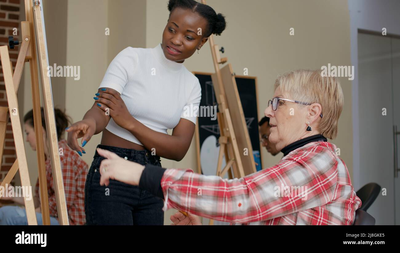 Art class teacher guiding senior student to draw sketch on canvas. Old ...