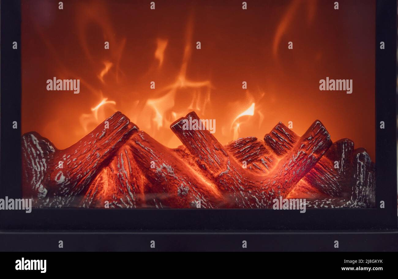 The logs of the fireplace burn with bright fire. Artificial decorative ...