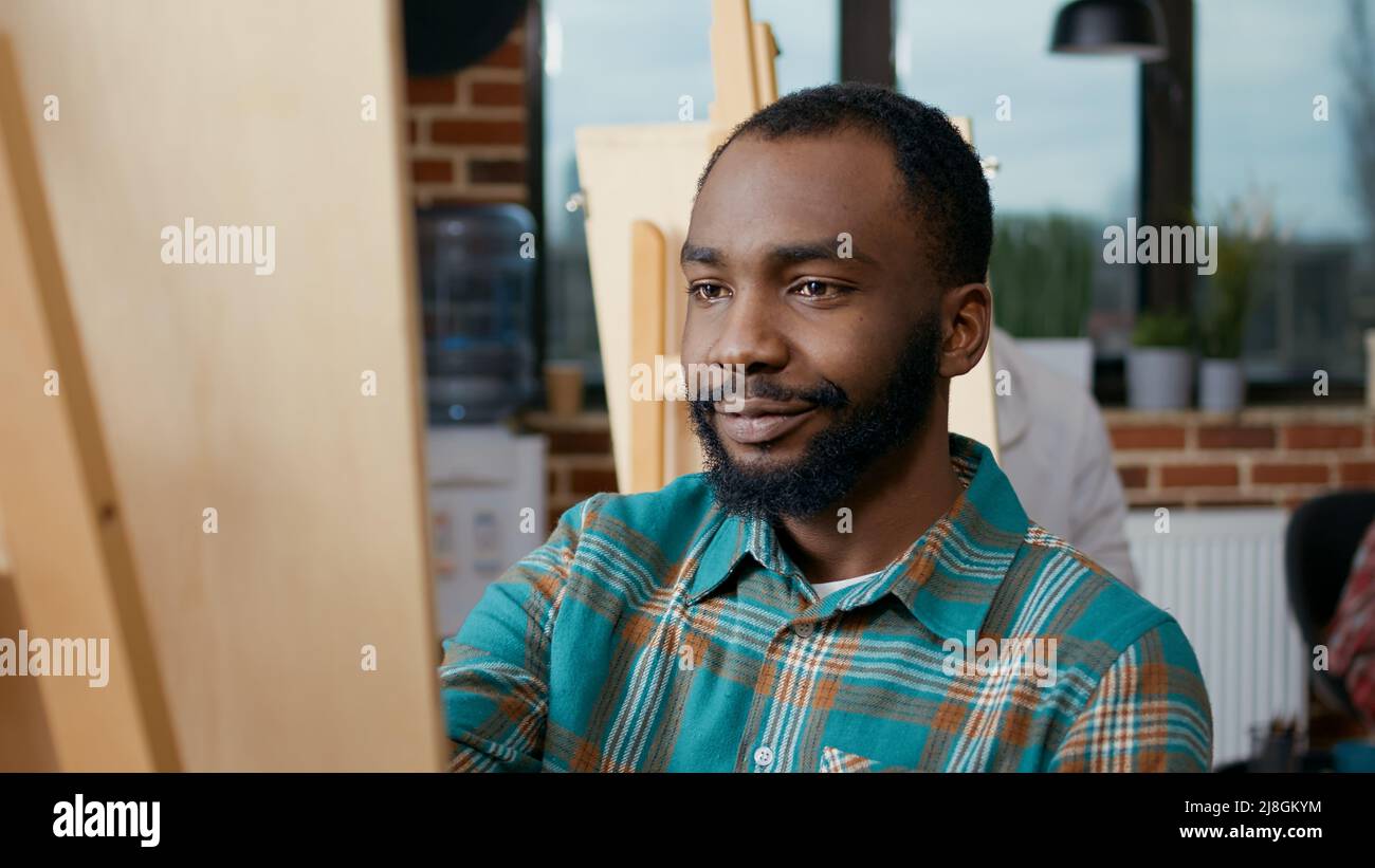 Portrait of african american man drawing on canvas in art class, paying ...