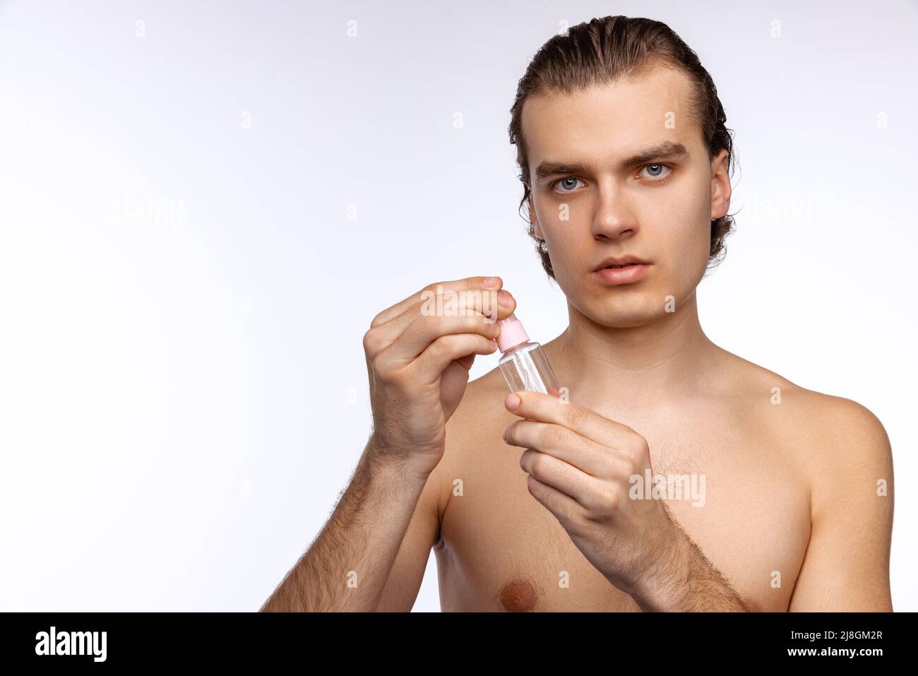 Portrait of young attractive man with perfect smooth skin, applying ...