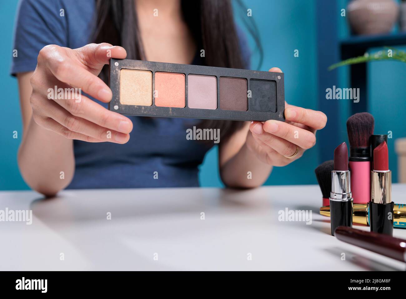 Social media influencer holding makeup palette doing cosmetic review ...