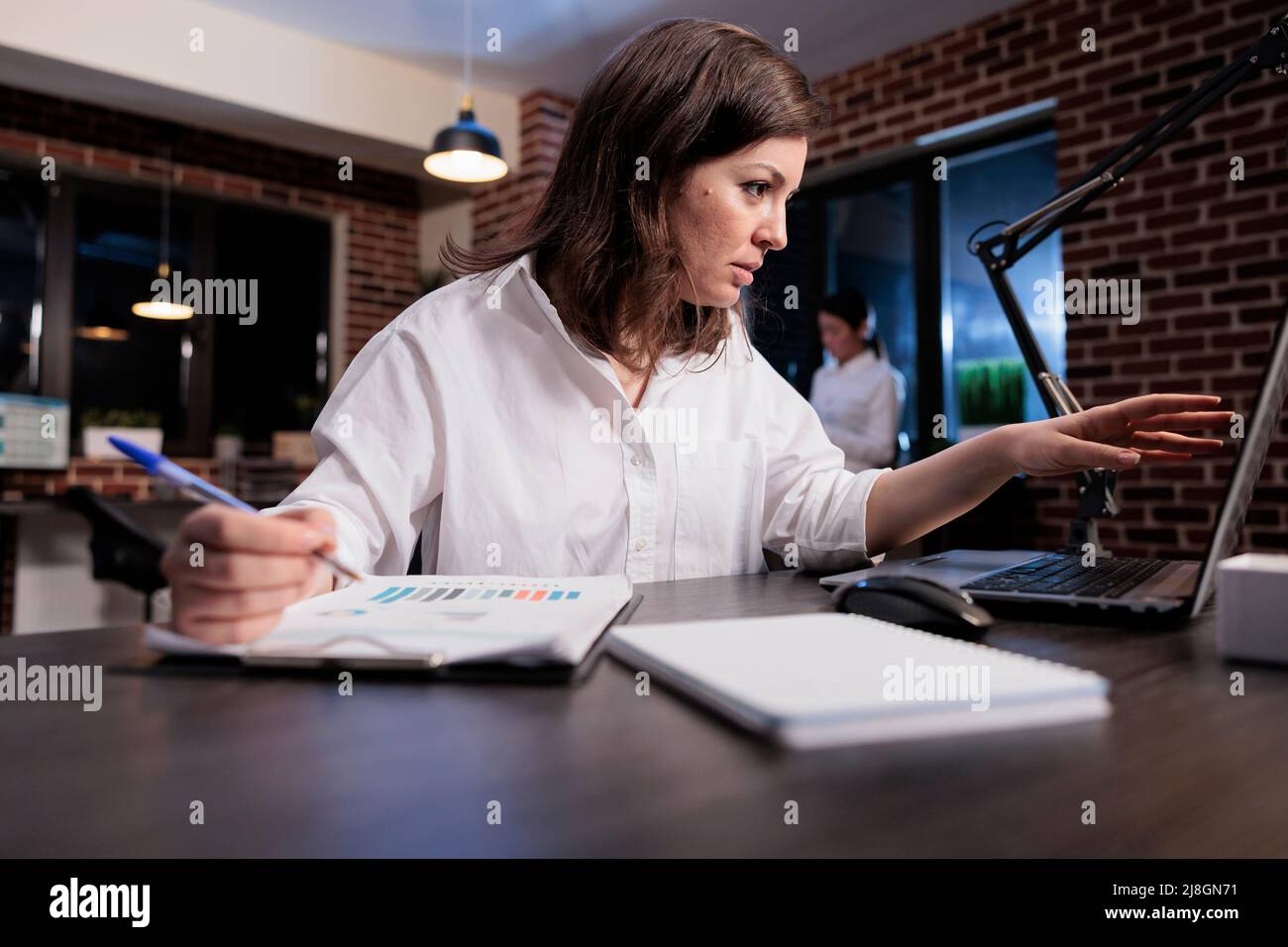 Business company employee comparing financial data from laptop with accounting documentation ...