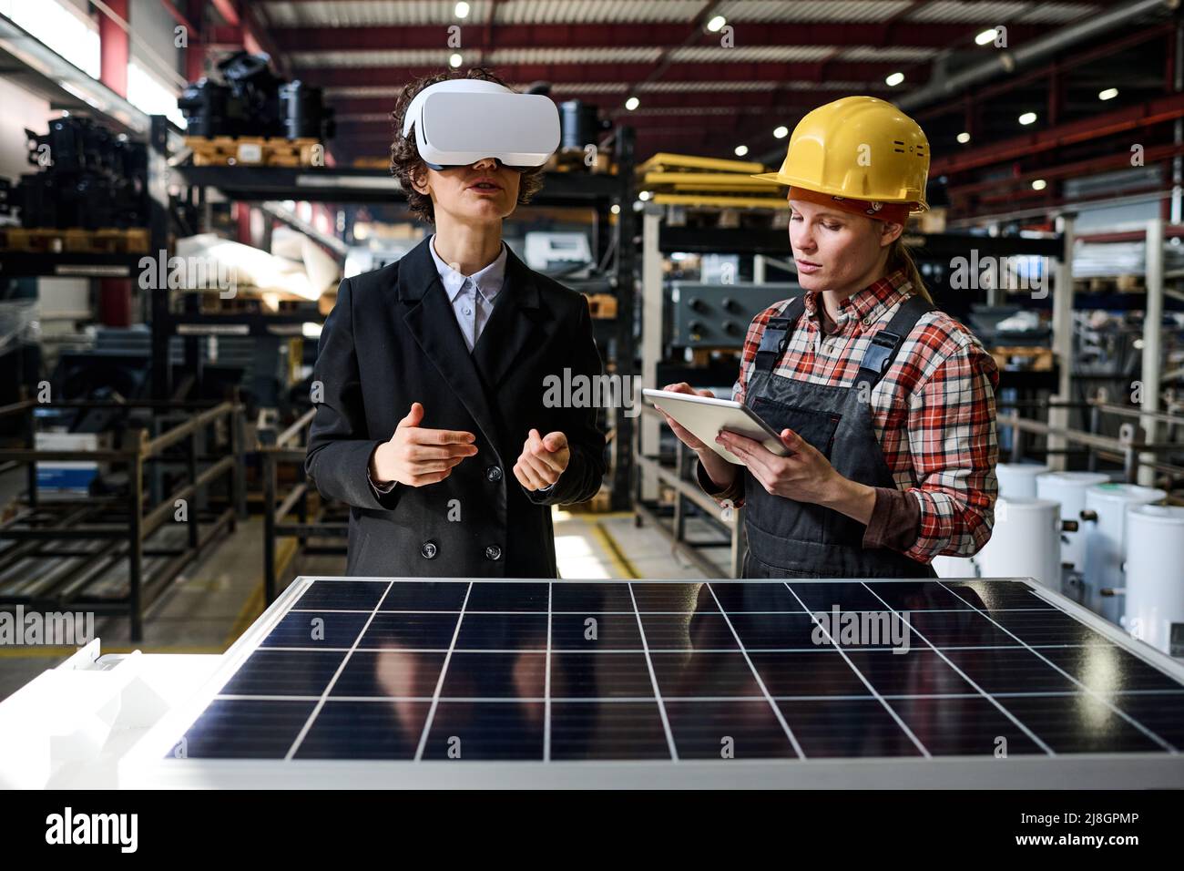 Young engineer using tablet while manager in vr headset making ...