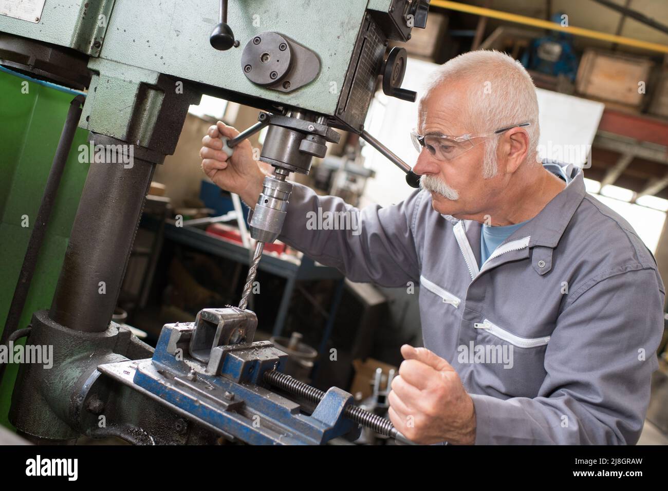 senior worker using bench drill Stock Photo - Alamy