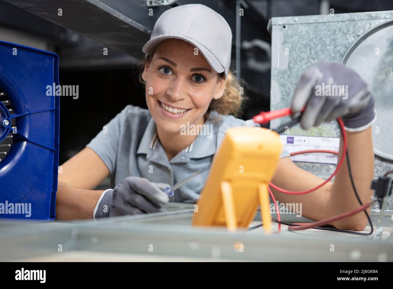 female elctrician fitting air conditions pipe in building ceiling Stock ...