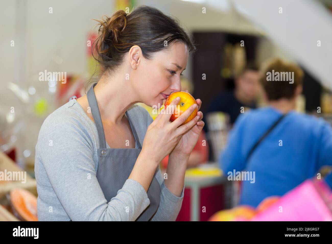portrait of grocer smelling apple Stock Photo - Alamy