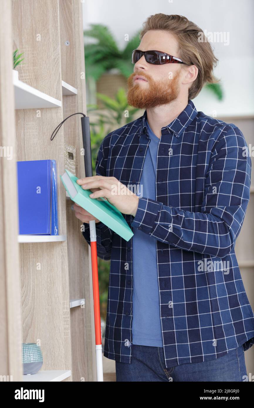 blind man trying to find the right for a book Stock Photo - Alamy