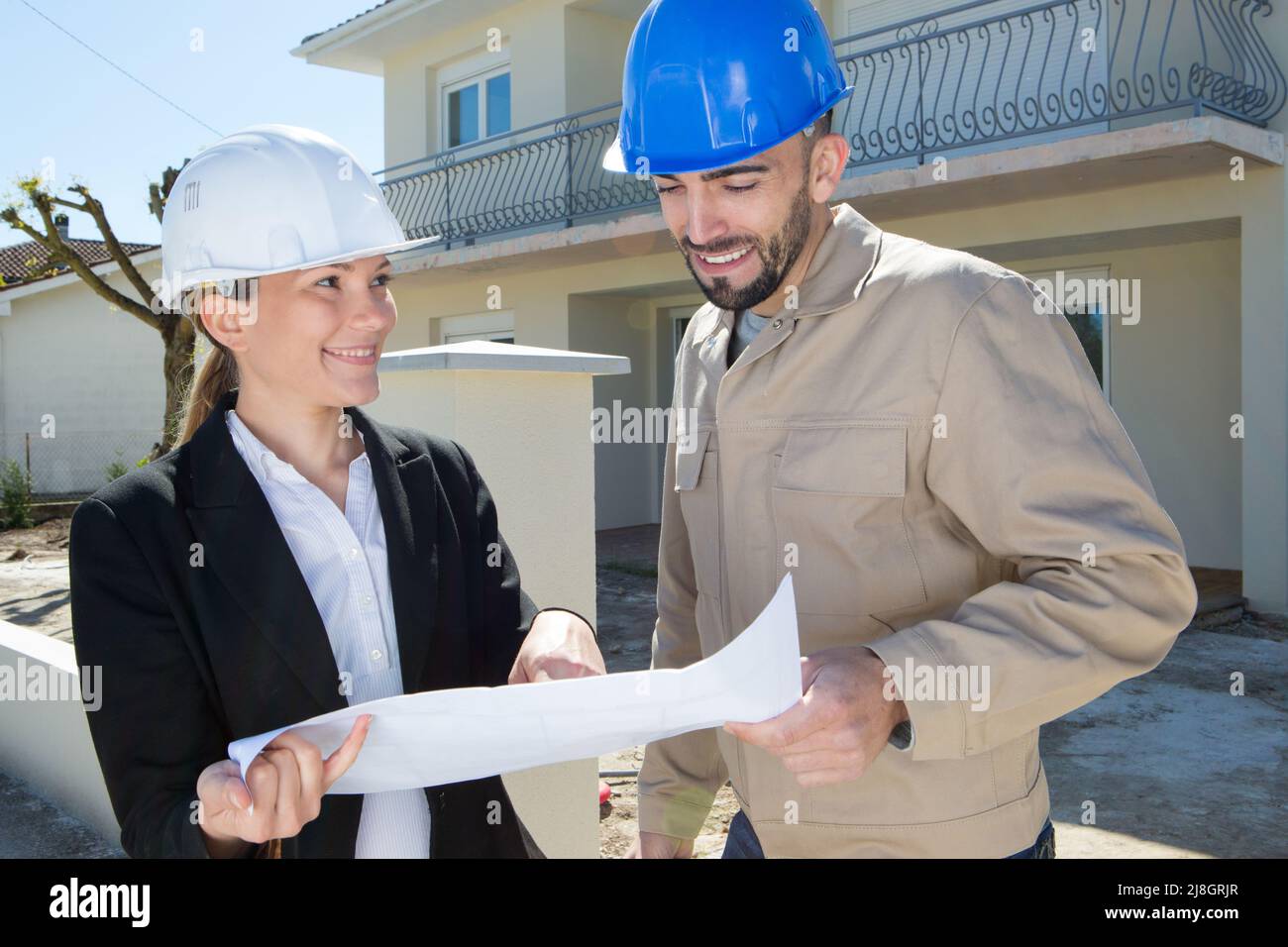 engineers wearing helmets discussing over plans outdoors Stock Photo ...