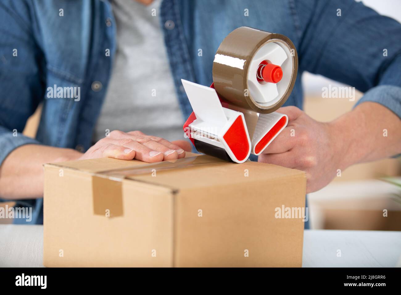 man applying adhesive tape on a packing box Stock Photo - Alamy