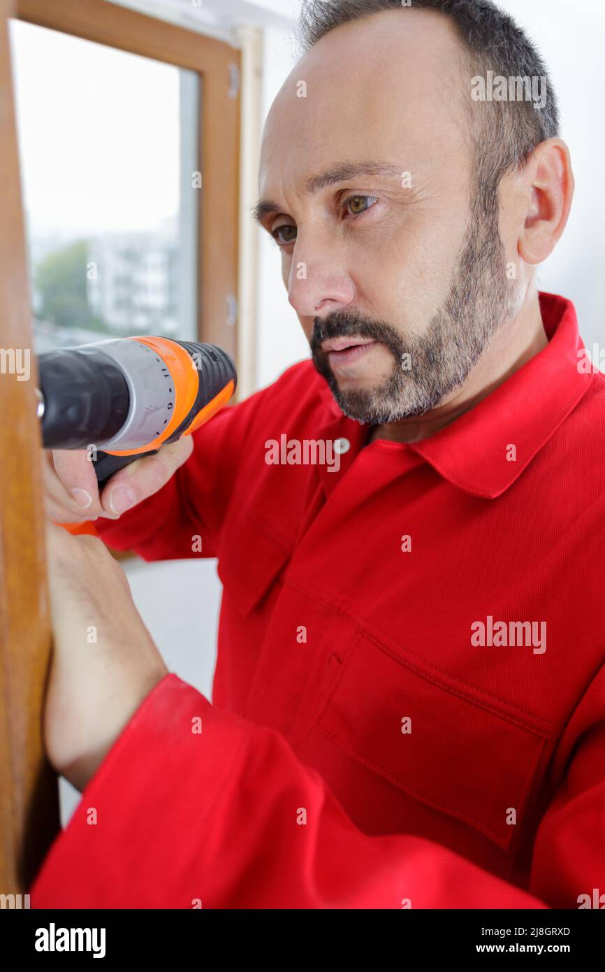 builder with drill inserting door frame to aperture Stock Photo - Alamy