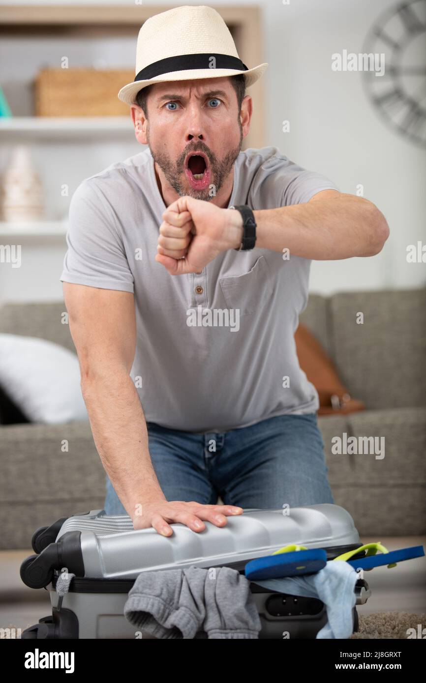 man packing suitcase looks at his watch in panic Stock Photo - Alamy