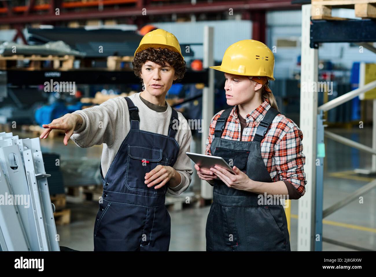 Confident female engineer pointing at industrial equipment during ...