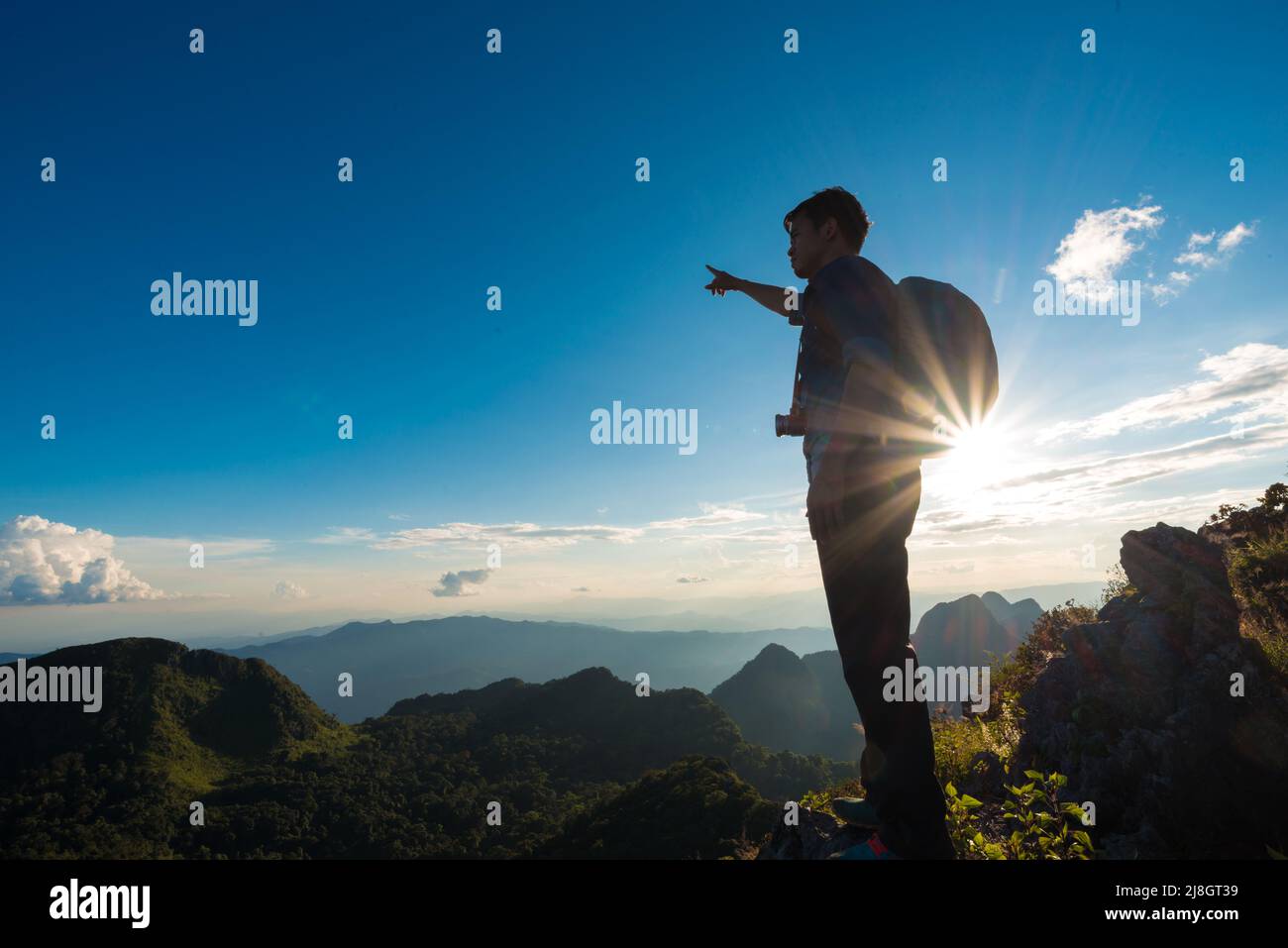 Photographer man standing on ledge of a mountain enjoying the beautiful ...