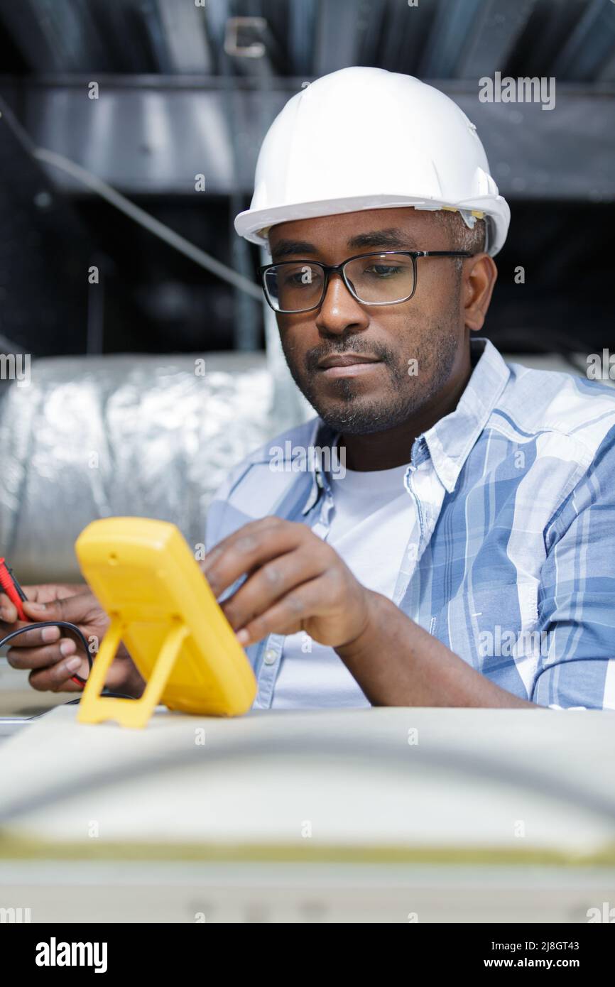 electrician using multimeter in roof space Stock Photo - Alamy