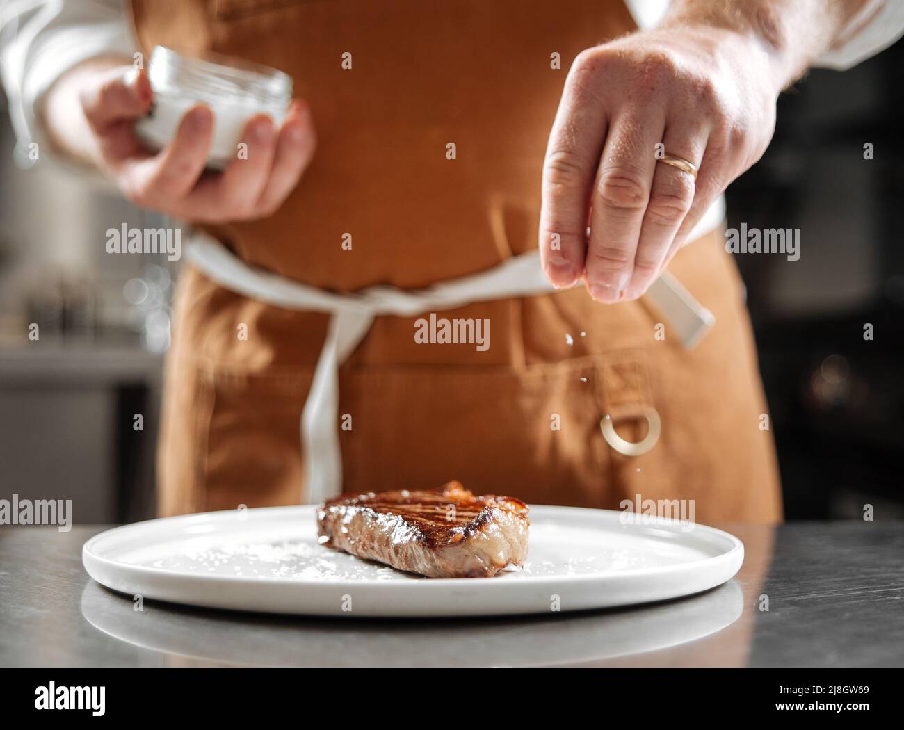 Chef's hands sprinkle cooked steak with salt Stock Photo - Alamy