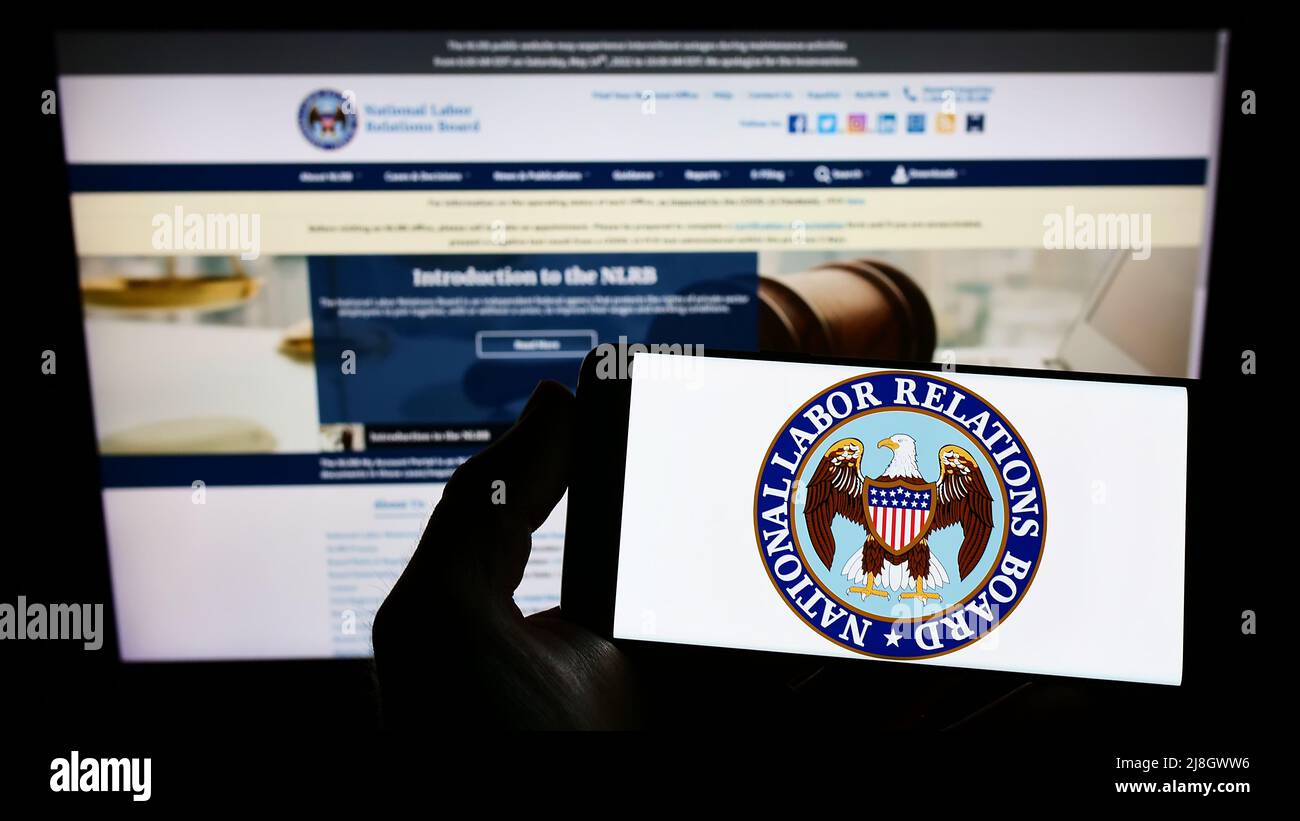 Person holding smartphone with logo of US National Labor Relations ...