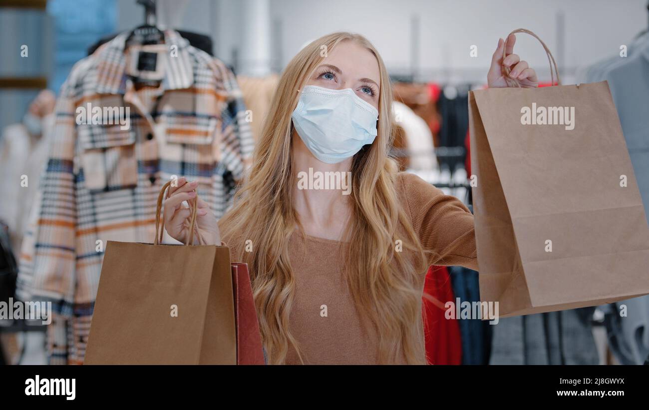 Rich happy blonde woman shopper wearing medical face protective mask ...
