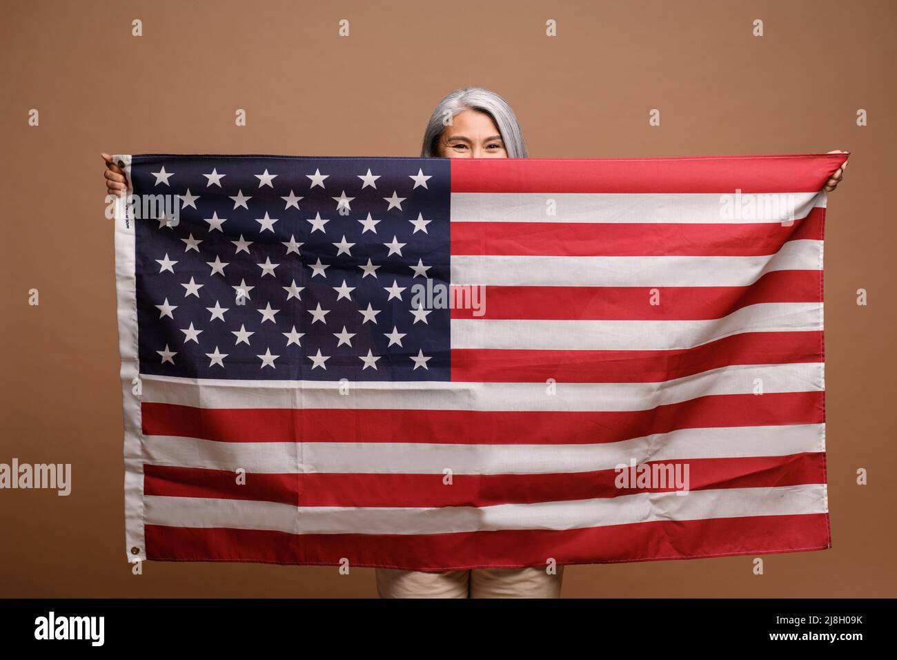 Happy and excited asian woman hiding behind the American flag while ...