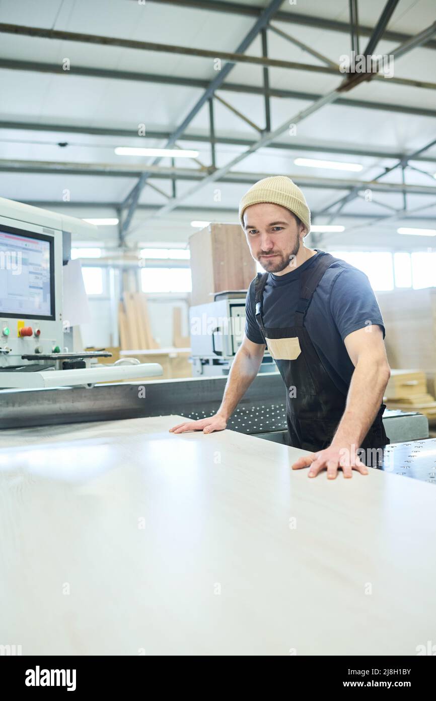 Young carpenter concentrating on his work with wooden plank while ...