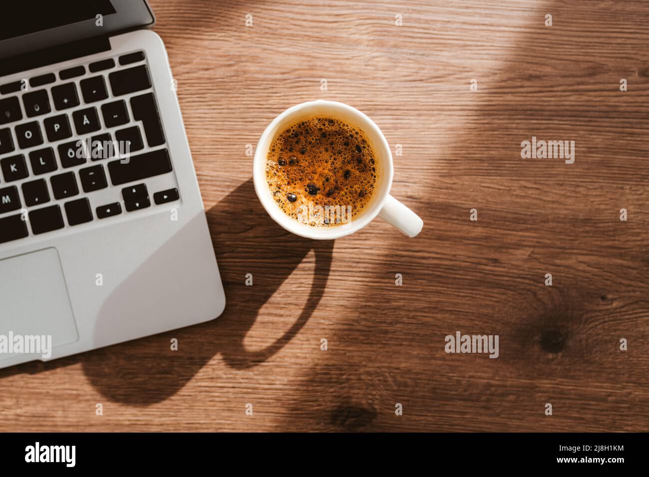 Cup of hot black coffee and laptop computer on home office desk, top ...