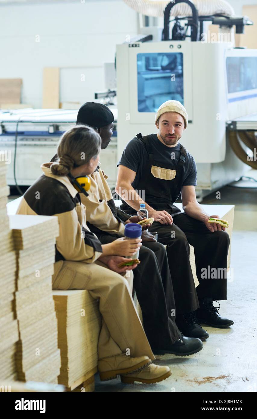 Group of workers in uniform drinking coffee and talking to each other ...