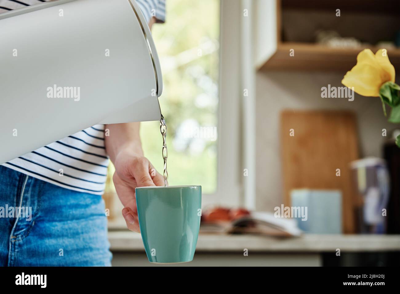 Tea time, Woman pouring boiled water from electric kettle into cup for ...