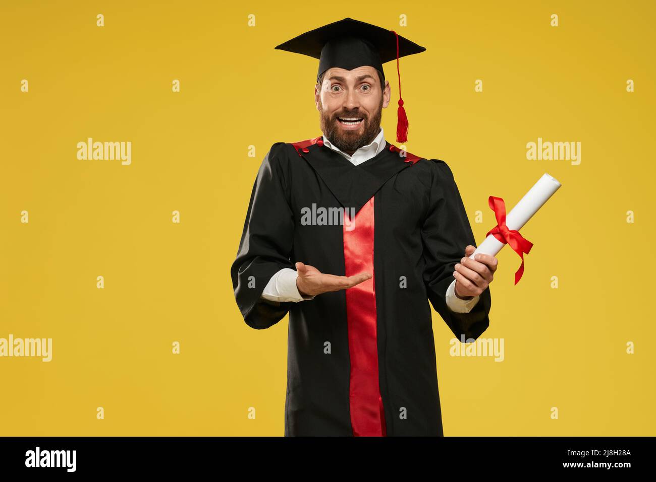 Front view of stdudent standing, holding diploma, surprised. Man with ...
