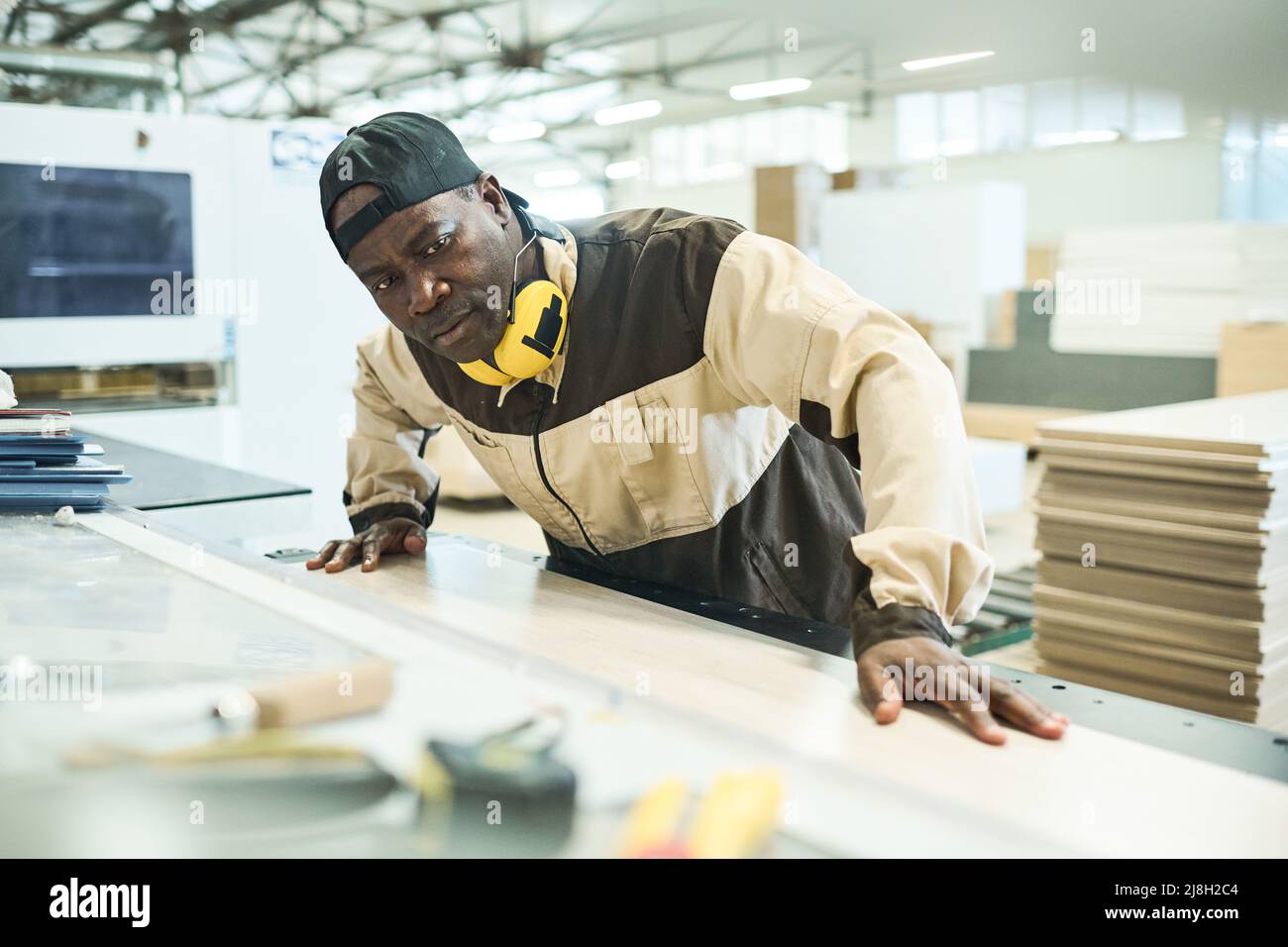 Serious African carpenter sawing wood on special machine during his ...