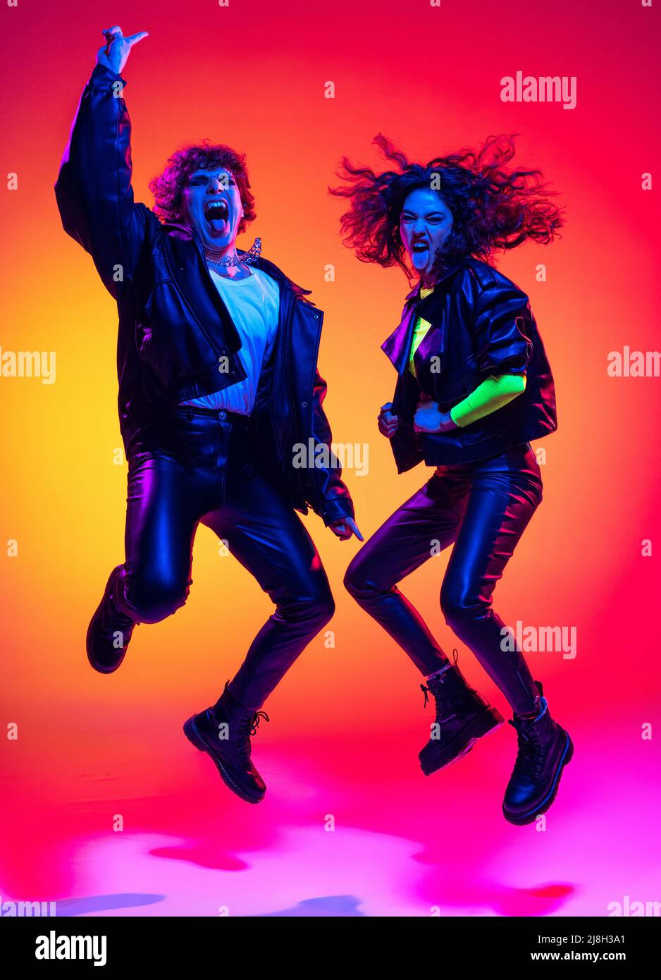 Excited young man and girl in black leather outfits having fun ...