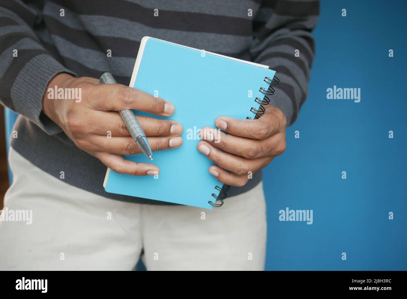 man hand holding a blue color notepad with pen Stock Photo - Alamy