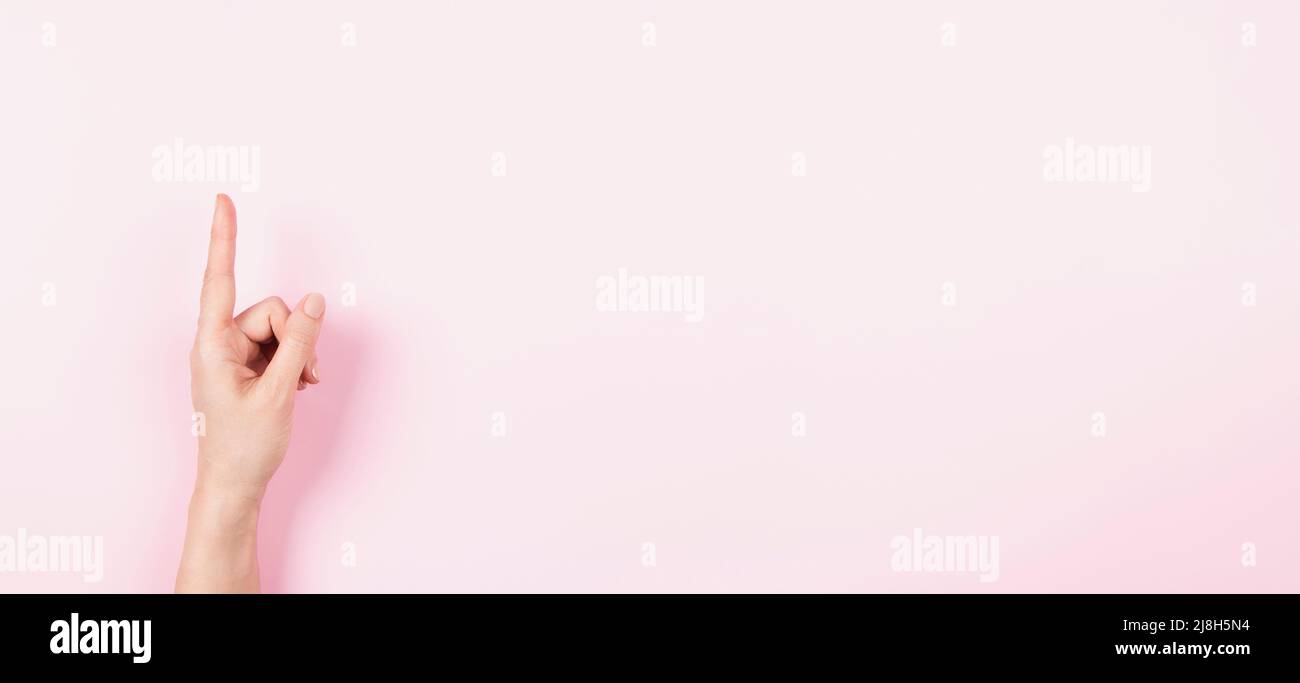 Hand gesture. Woman hand pointing up with index finger to something virtual and invisible, copy ...