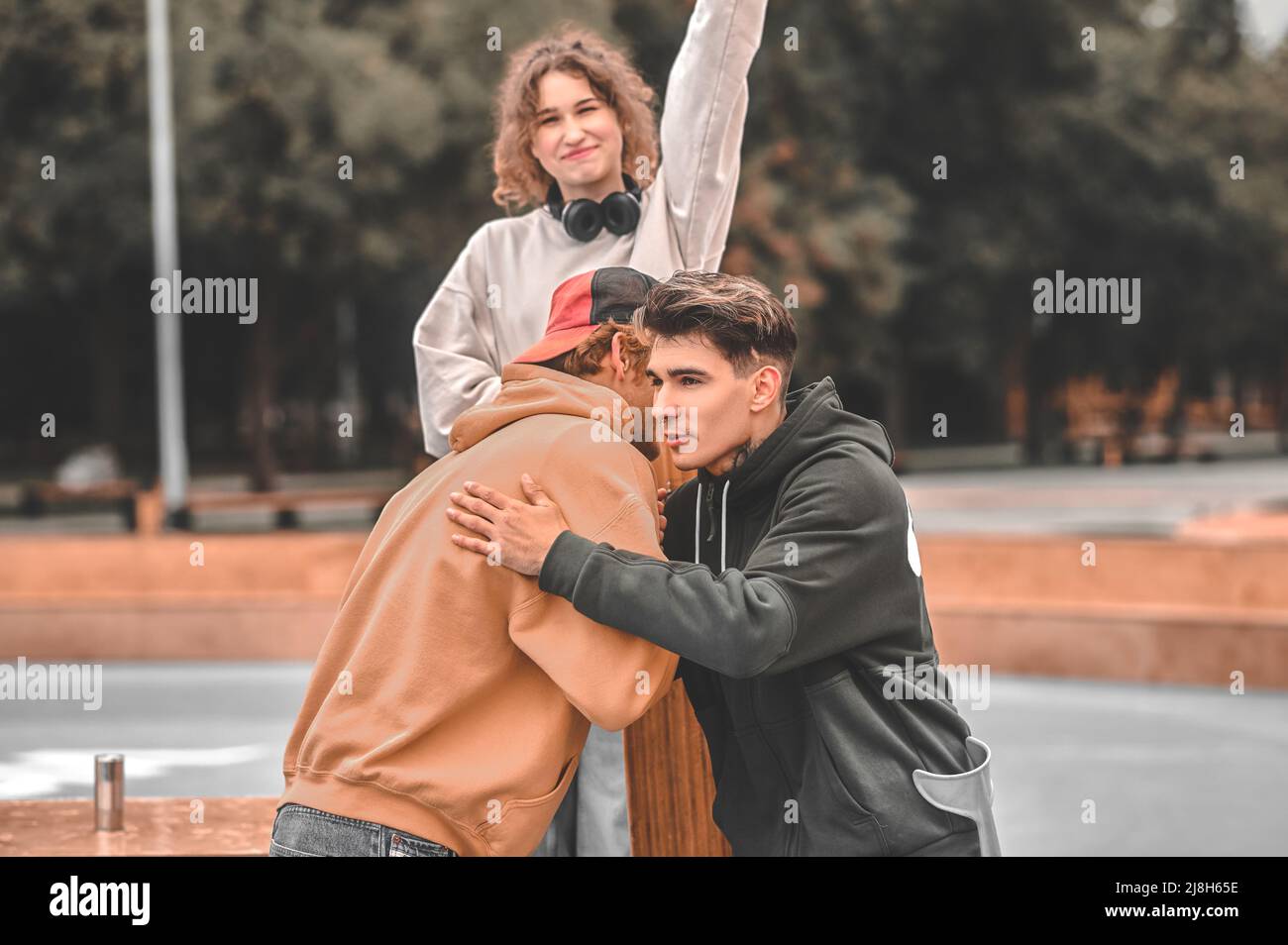 Girl looking at camera and two friends hugging Stock Photo - Alamy