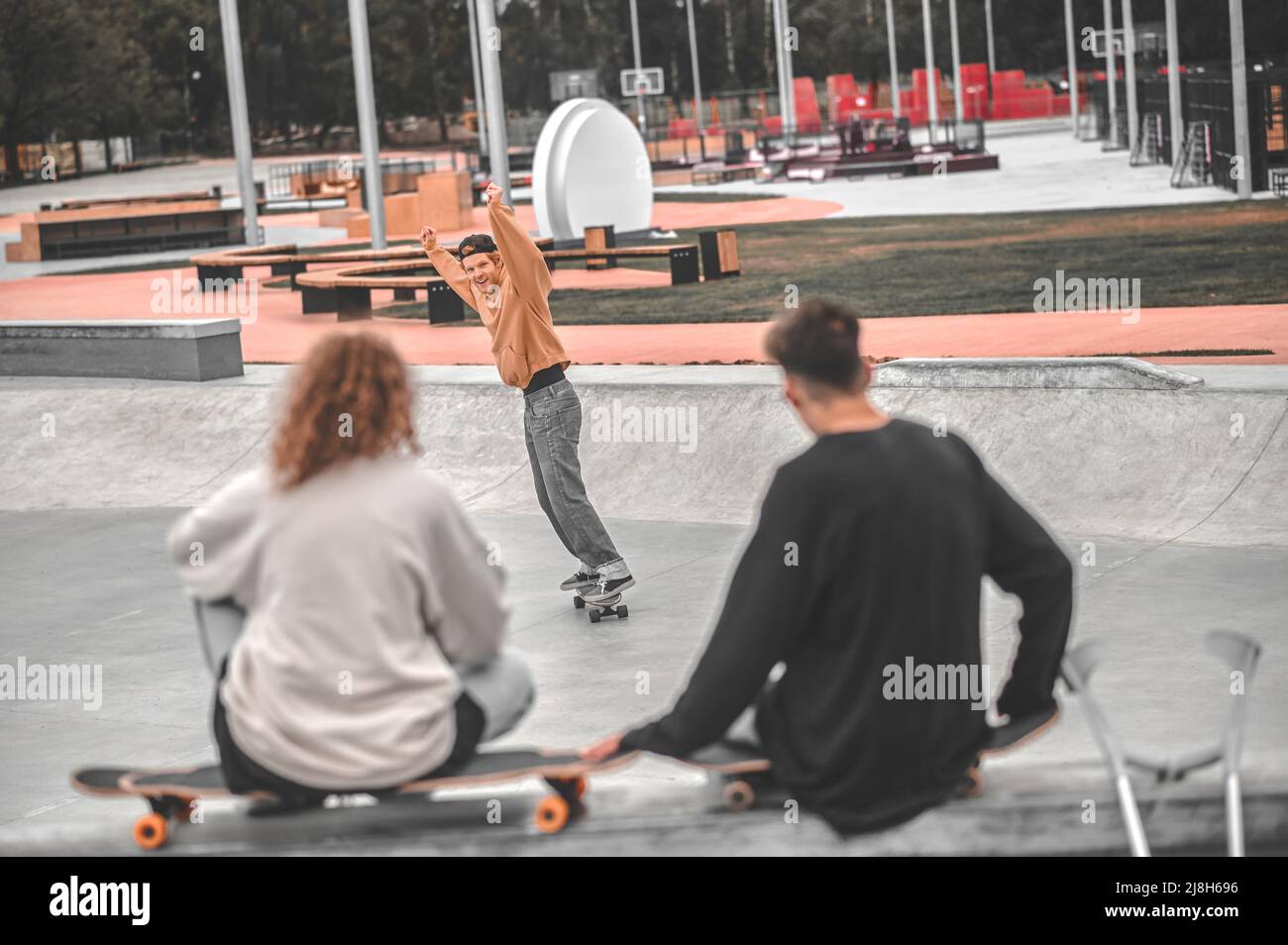 Guy sliding on skateboard and friends with back Stock Photo - Alamy