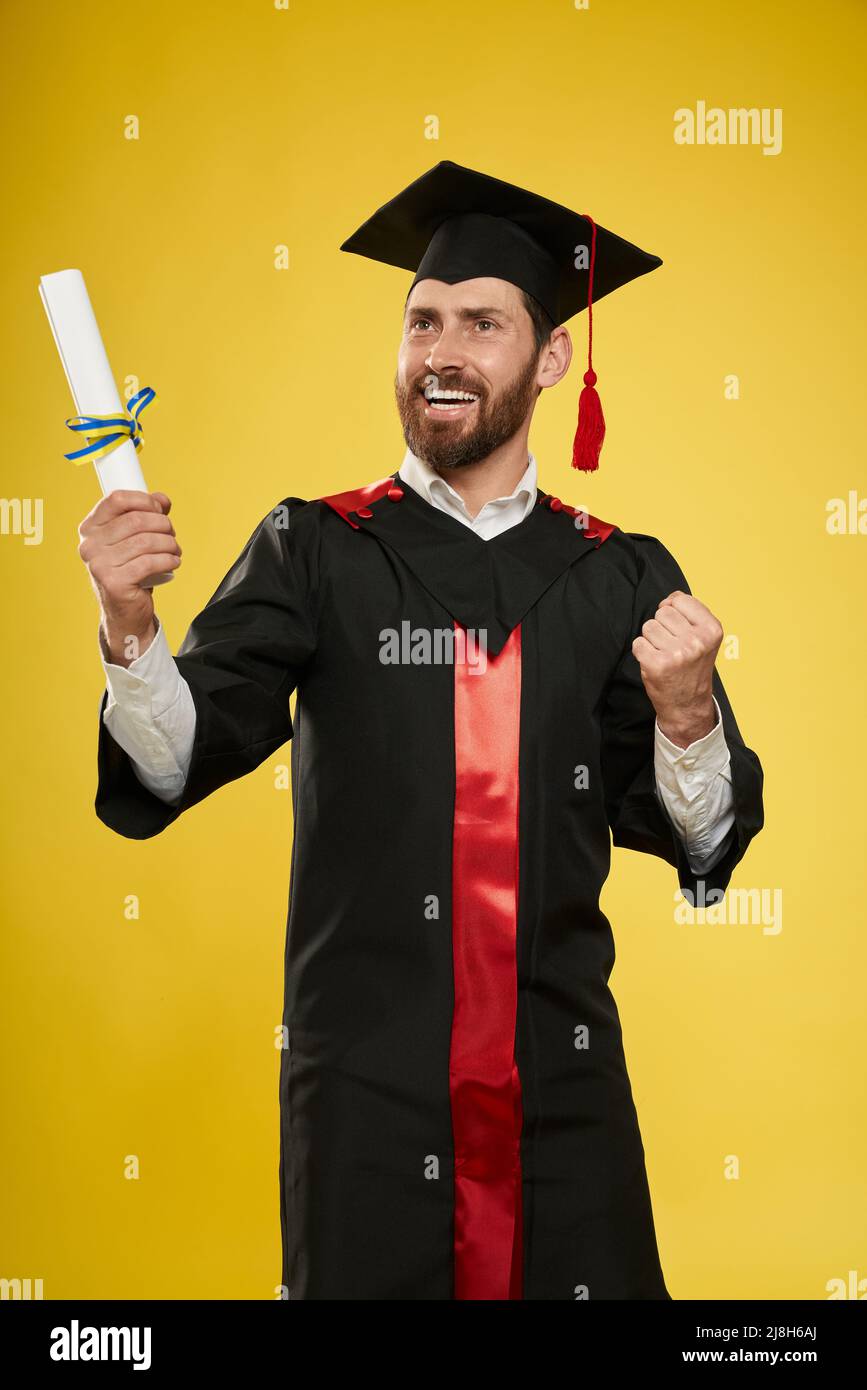 Front view of graduate with beard holding diploma, showing hurray. Man ...